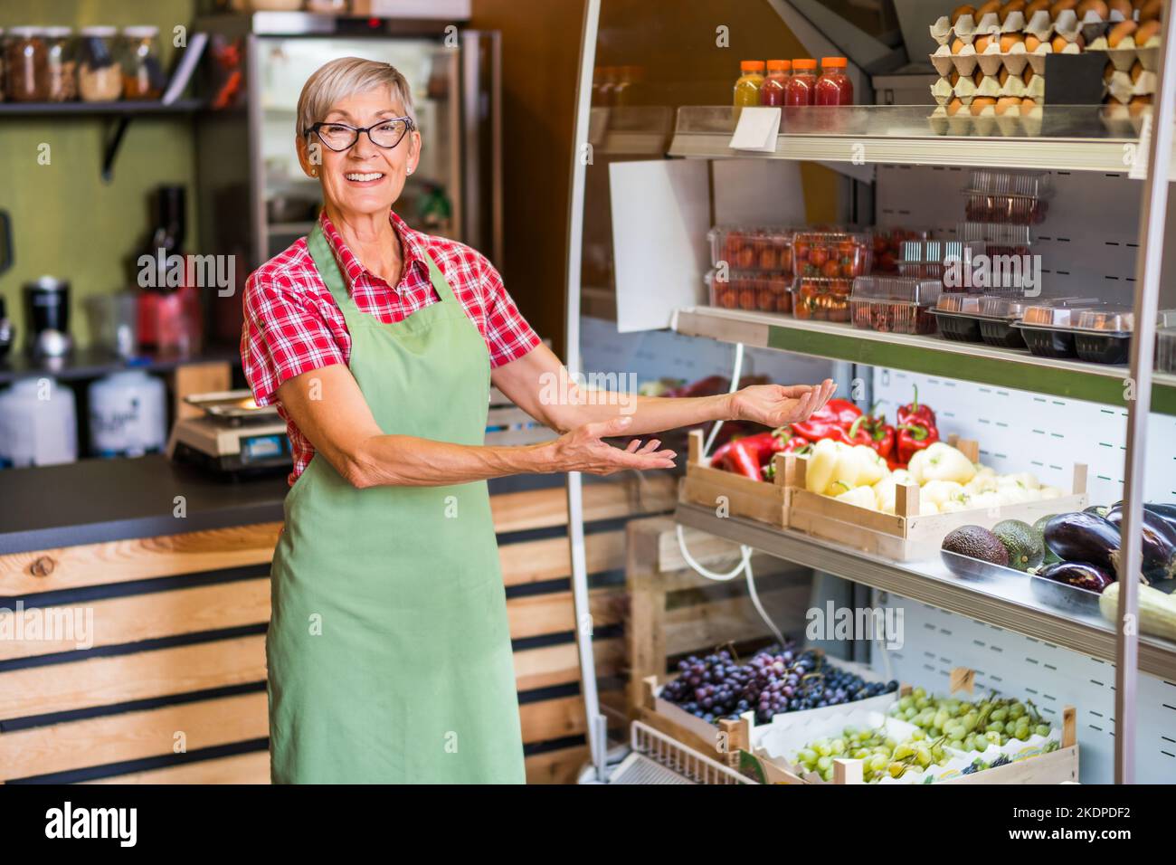 Mature woman works in fruits and vegetables shop. Portrait of small ...