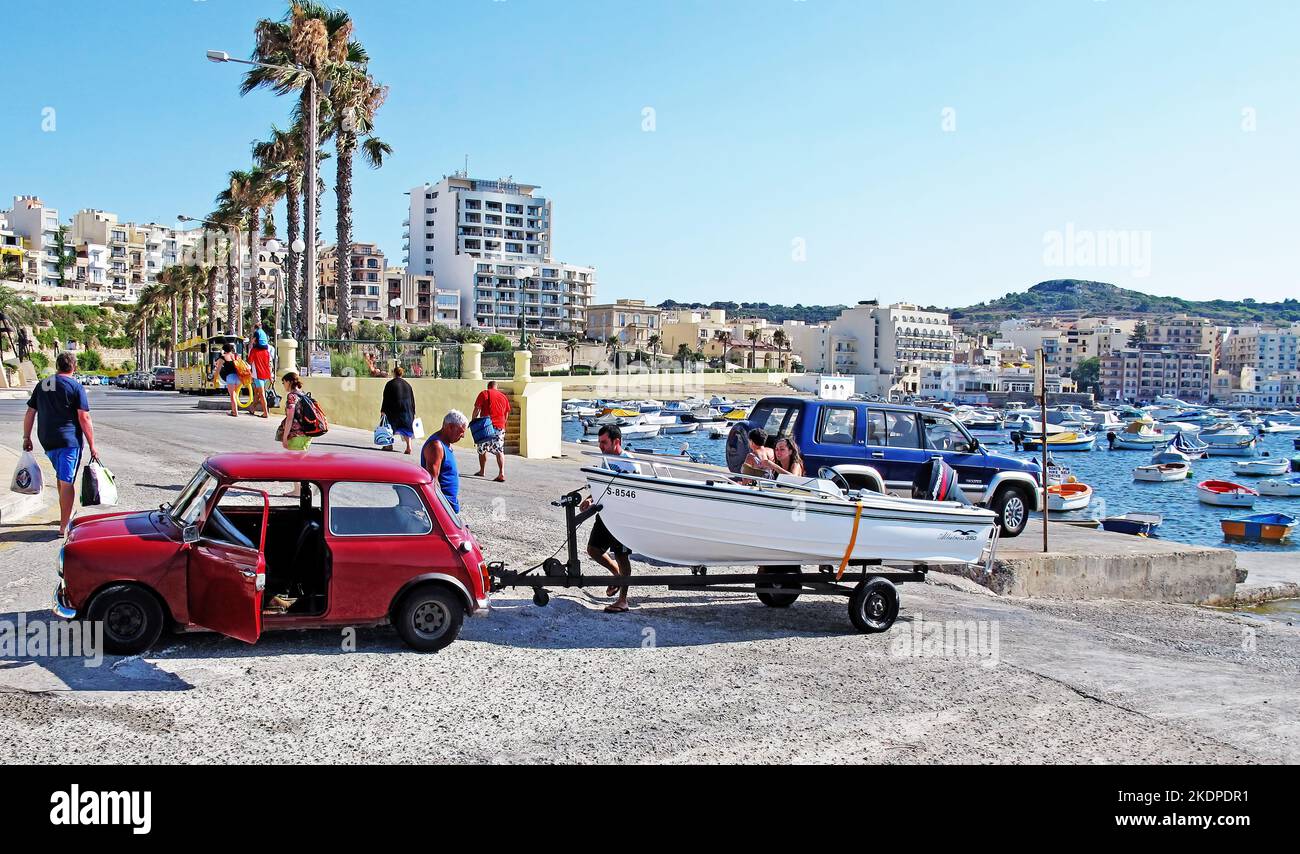 Bugibba, Malta - July 12, 2012: two men are pulling a boat ashore with ...