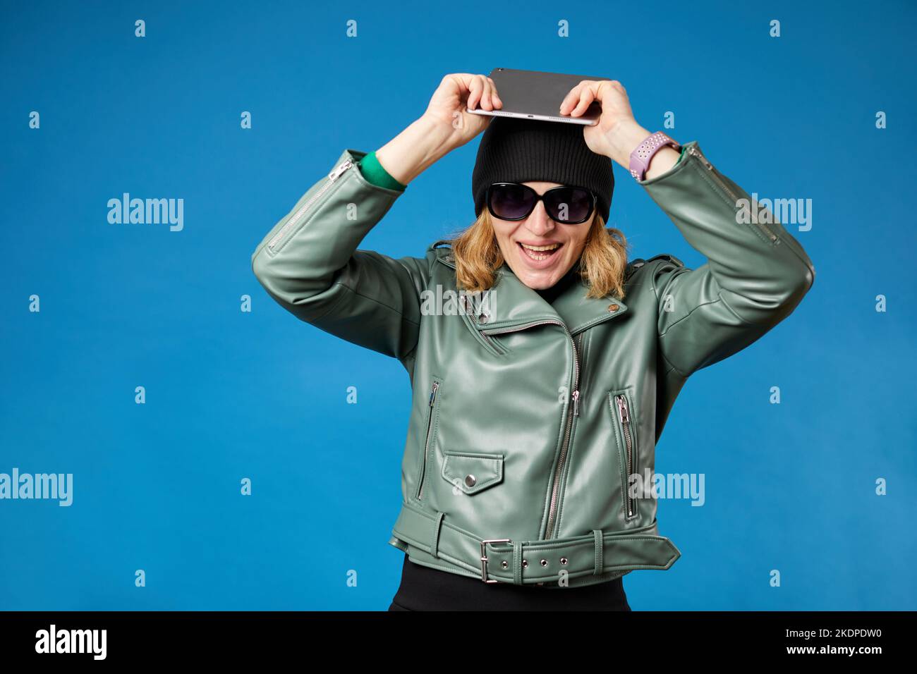 Young woman holding digital tablet with blank screen above head and ...