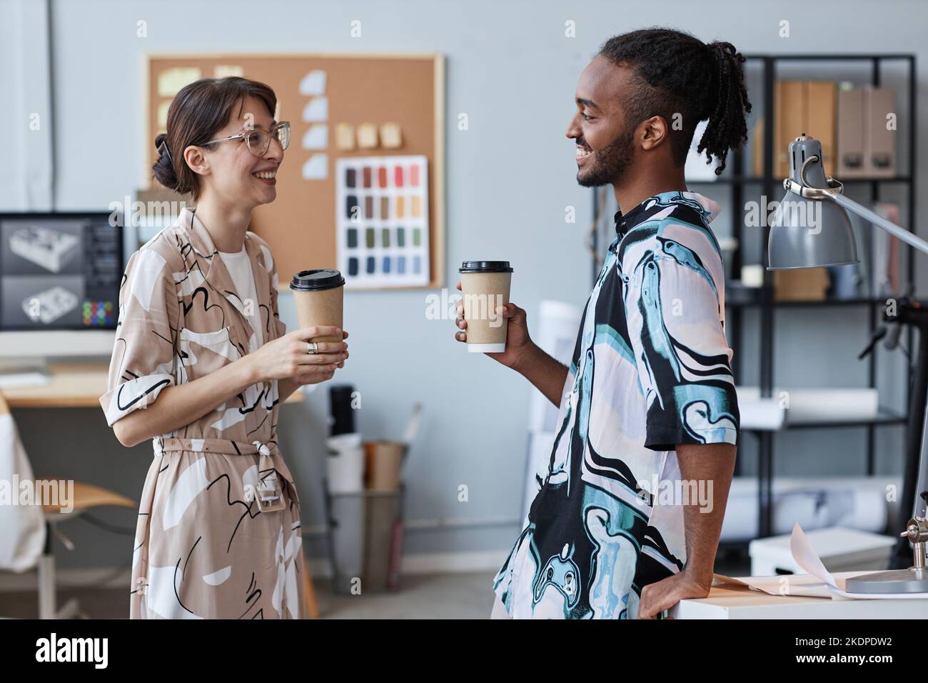 Side view portrait of two young coworkers chatting in office and ...