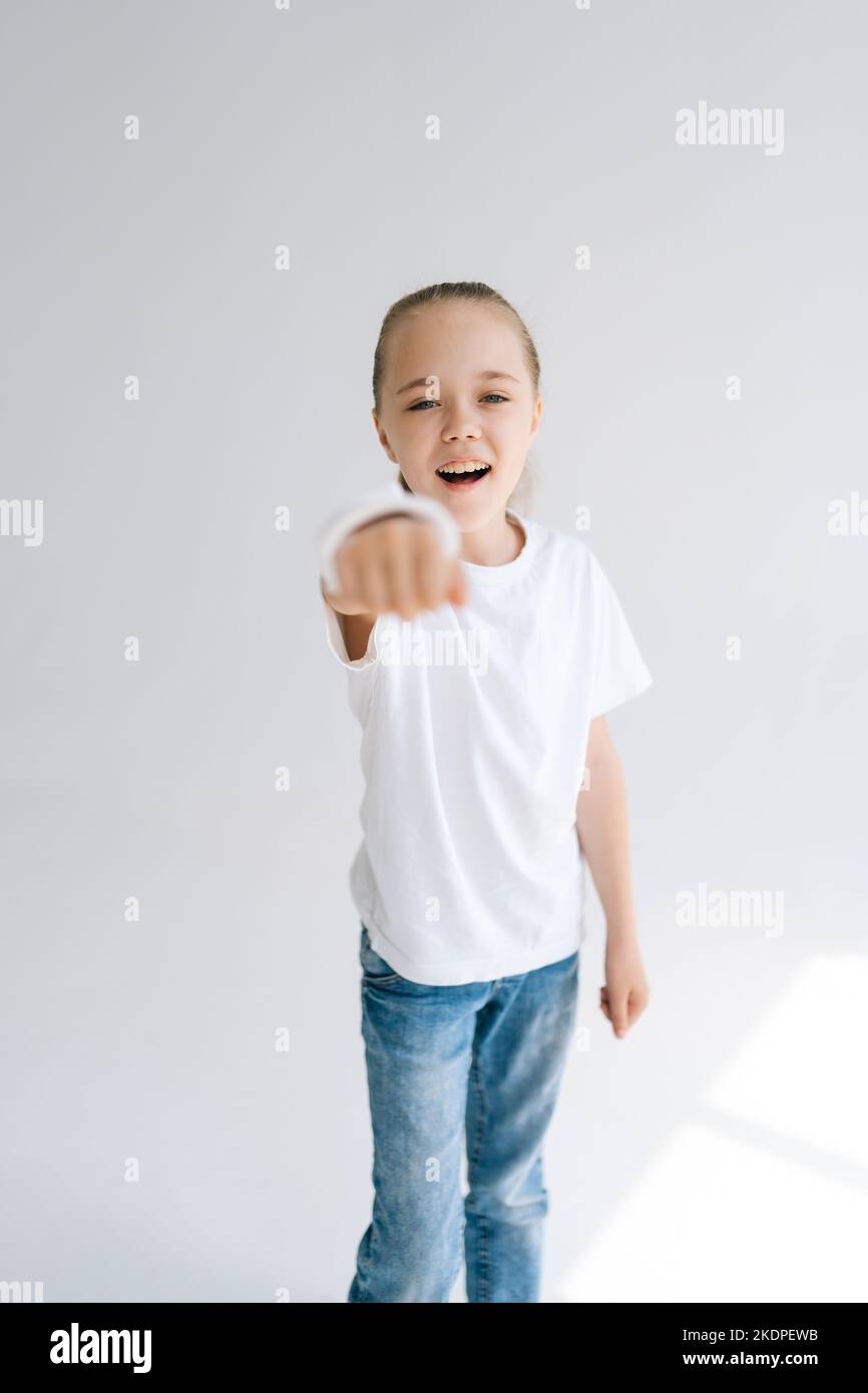 Vertical portrait of brave smiling little girl with broken hand wrapped ...