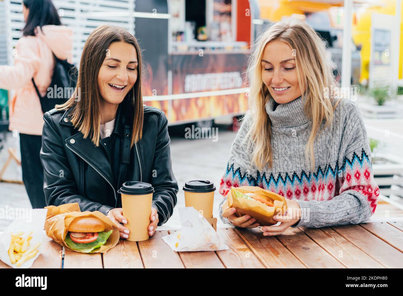 Two satisfied happy hungry women eat burgers in the street market Stock ...