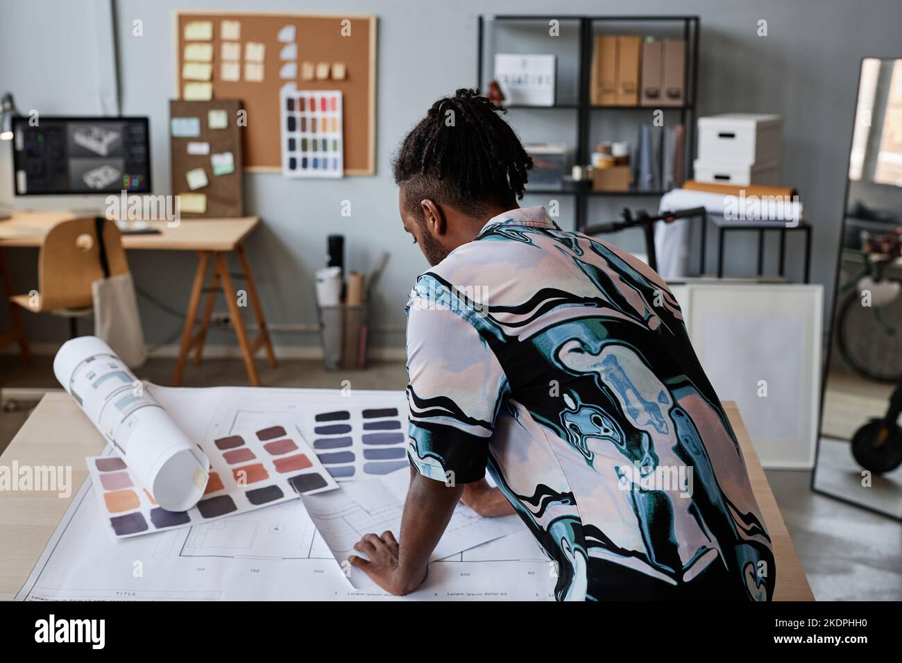 Back view portrait of male architect working on floor plans in office ...