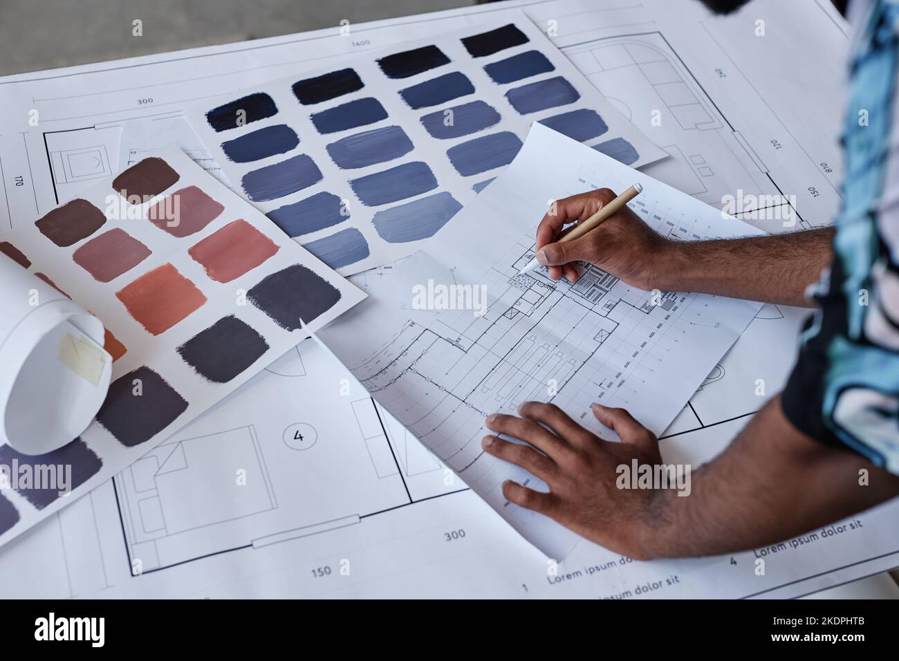 Close up of male architect working on floor plans and color swatches ...