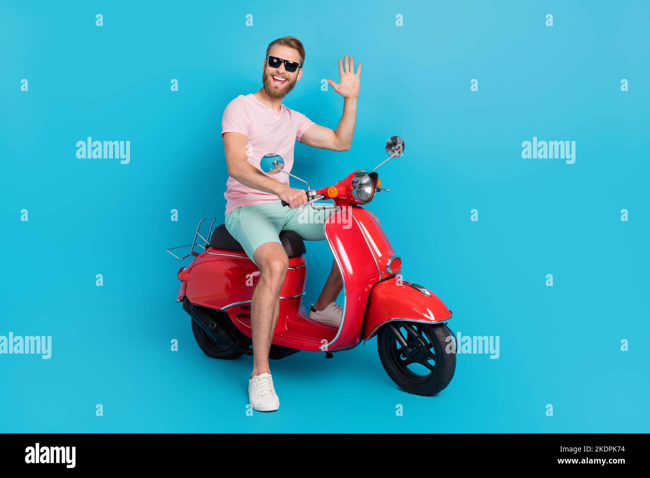 Full body photo of attractive young man waving arm hello motorcyclist ...