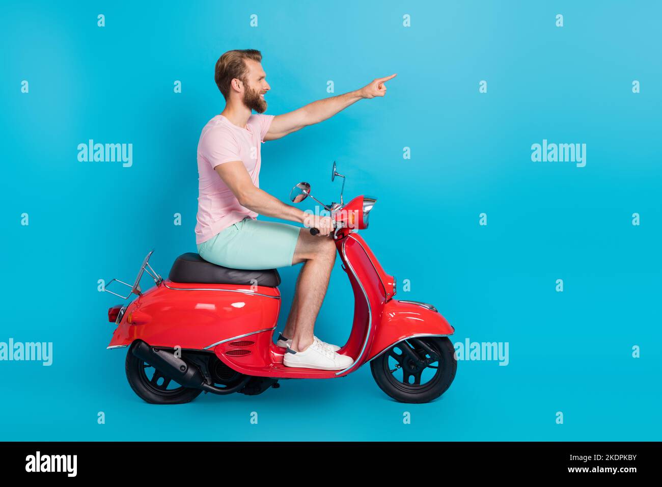 Full body photo of nice young man riding scooter arm pointing forward ...