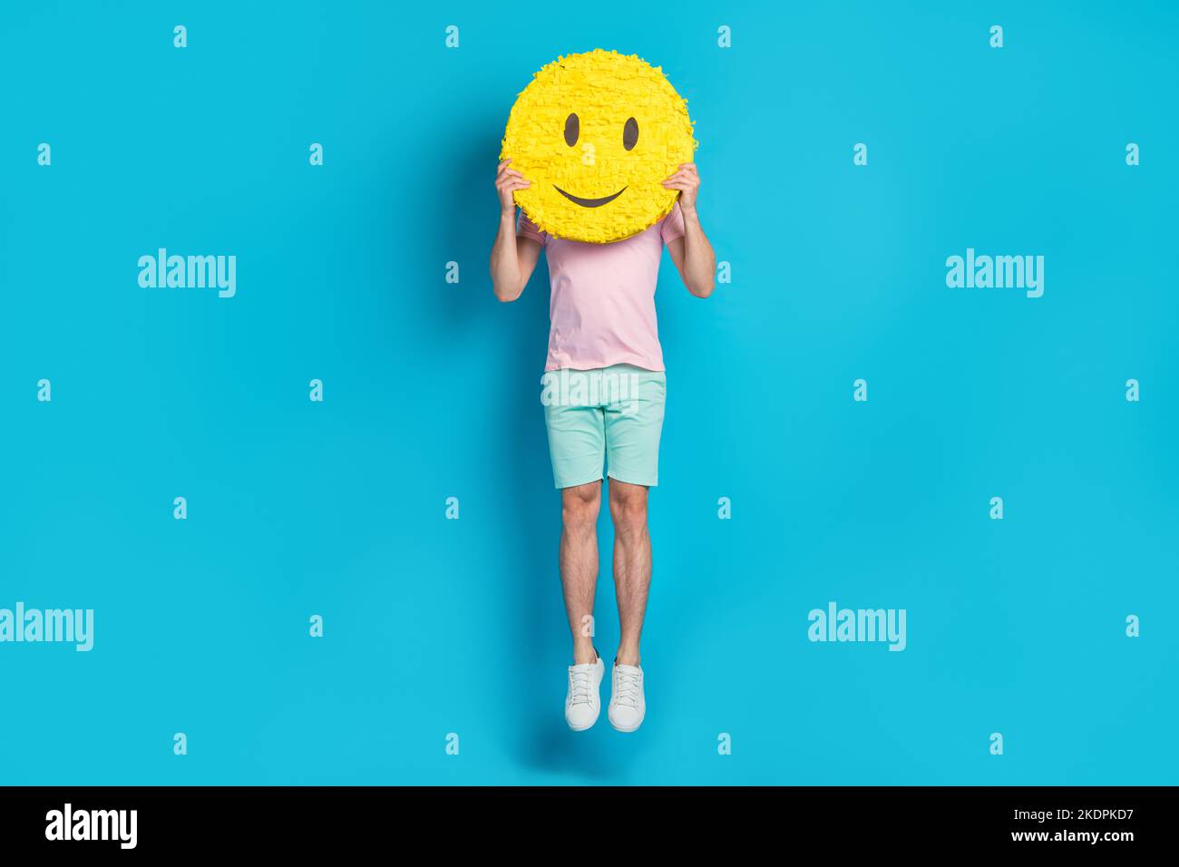 Full size photo of handsome young man jump hide face emoticon pinata ...