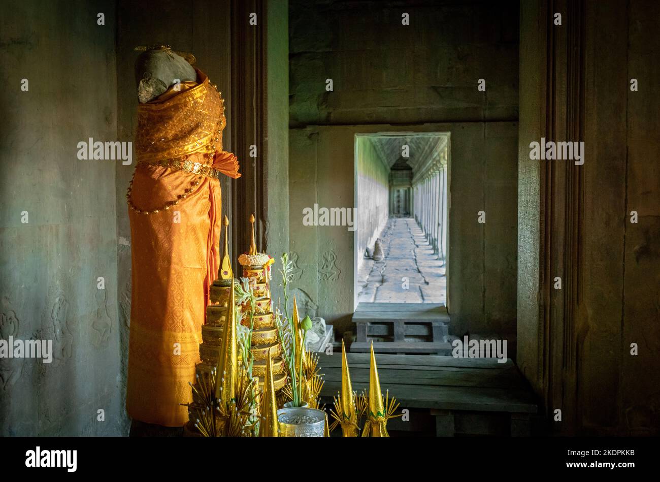 An ancient statue is dressed in orange robes at a Buddhist shrine ...