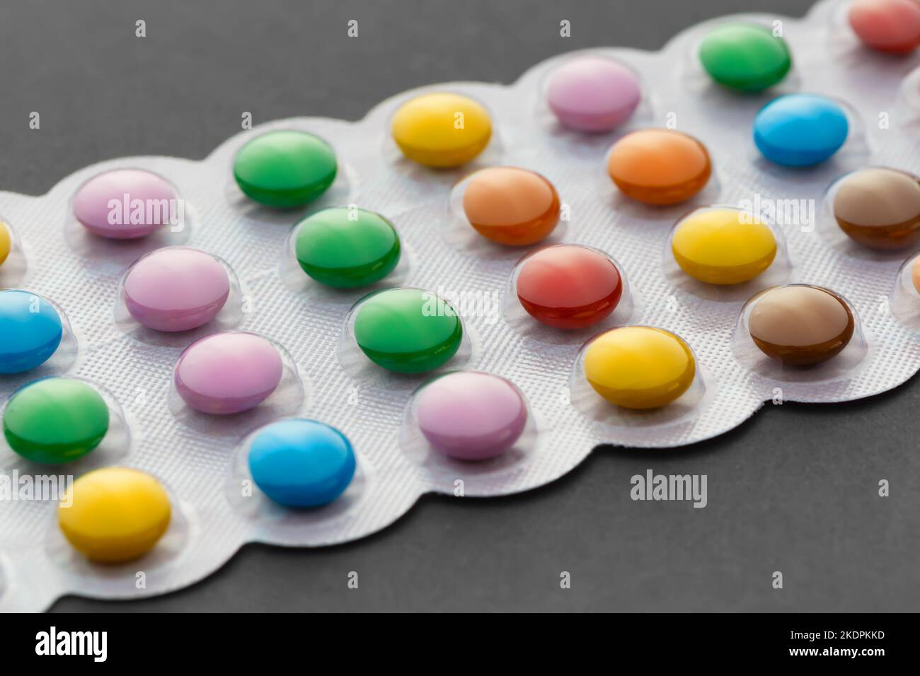 Multi-colored pills in a blister pack close-up on a gray background ...
