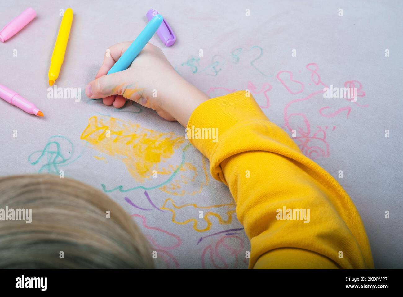 The child hand drawing with felt-tip pen on the upholstery of the couch ...