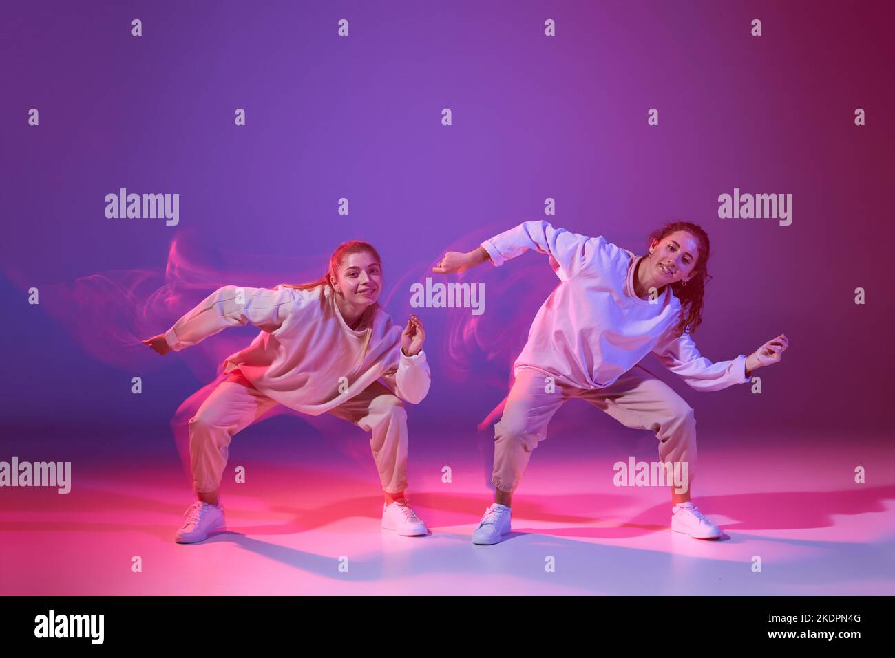 Portrait of two young girls dancing hip-hop isolated over gradient ...