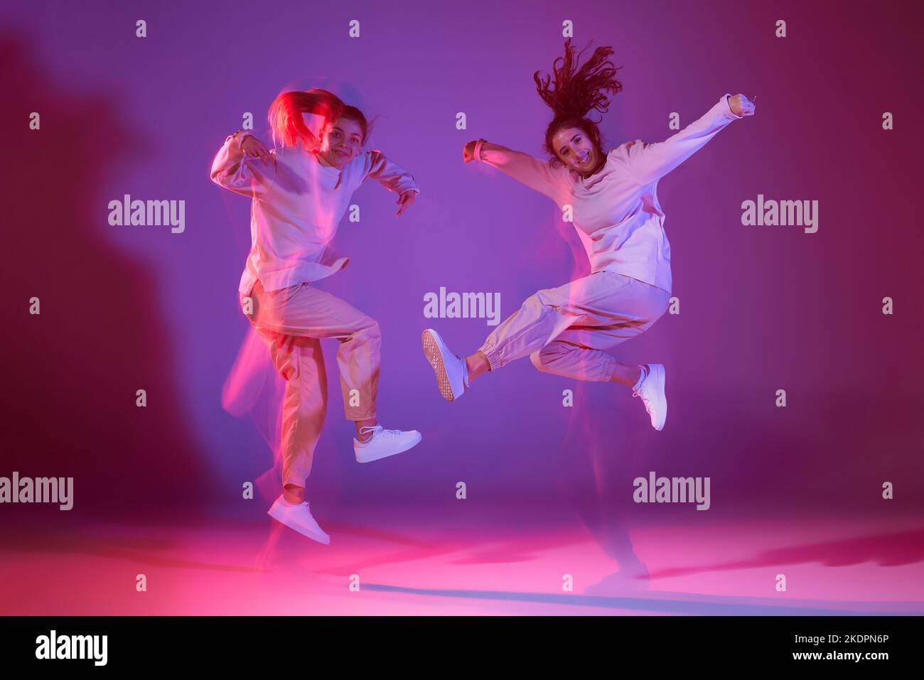 Portrait of two young girls dancing hip-hop isolated over gradient ...