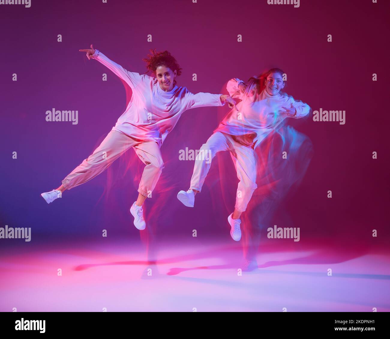 Portrait of two young girls dancing hip-hop isolated over gradient ...