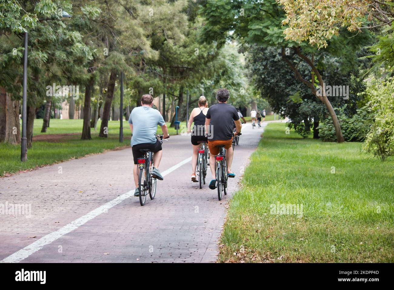 Cyclists riding on bikes cycling on a cycle path in a public park in ...