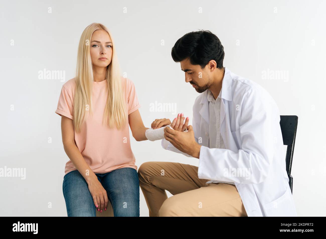 Studio portrait of male doctor in uniform consulting pretty injured ...