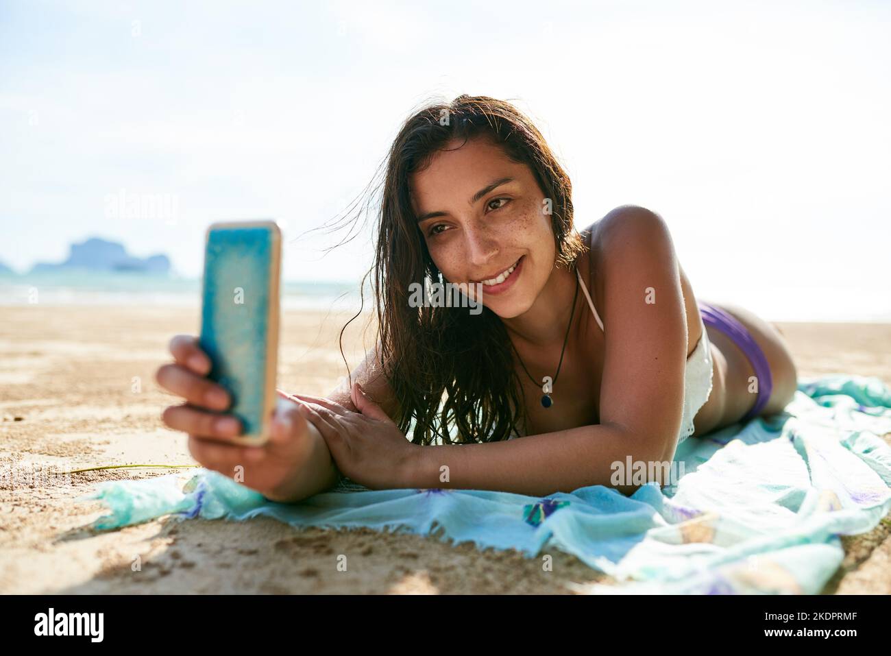 Beach selfies. a young woman taking a selfie while lying on the beach Stock Photo - Alamy