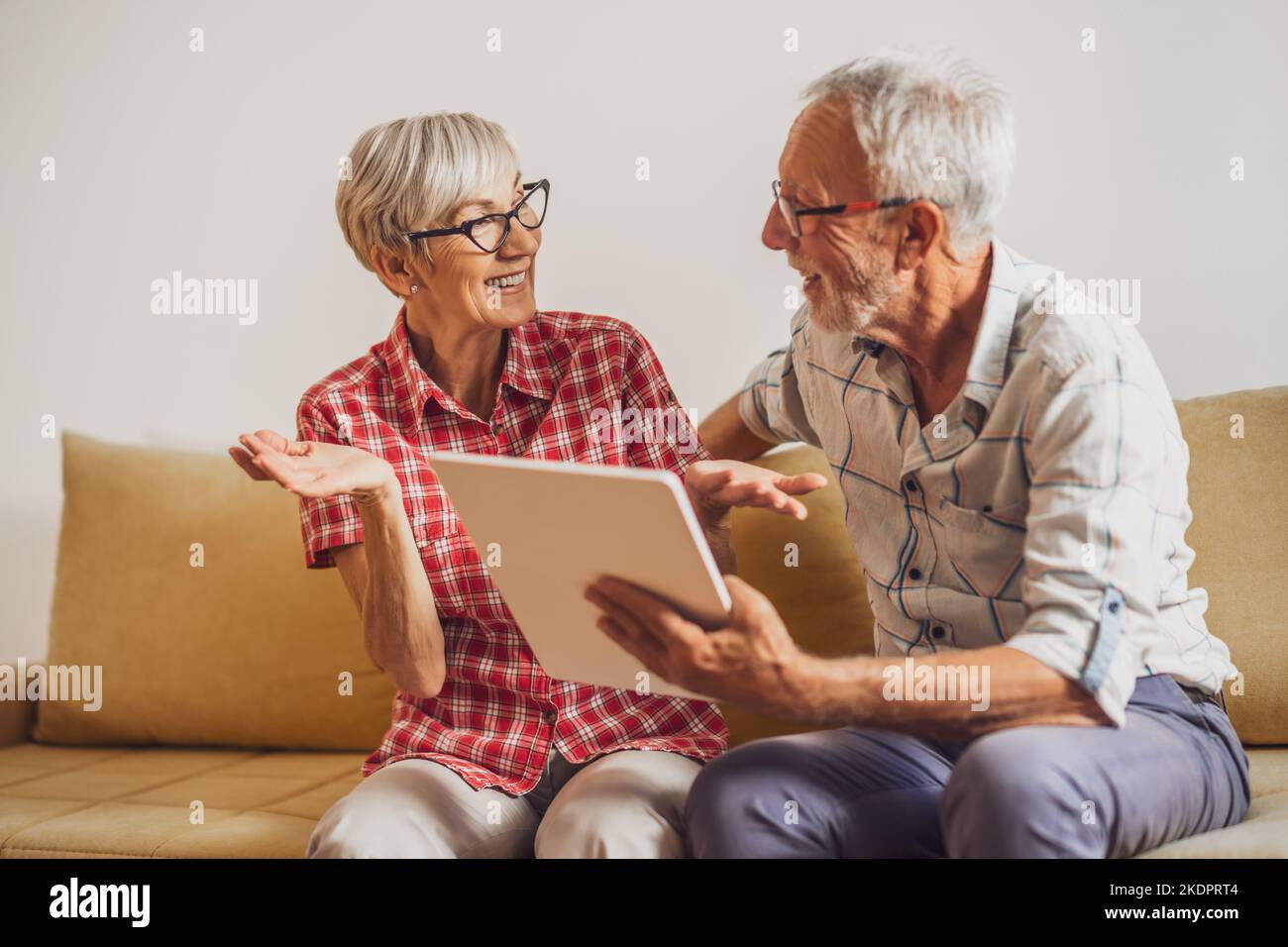 Senior couple sitting in living room and chatting with their family on ...