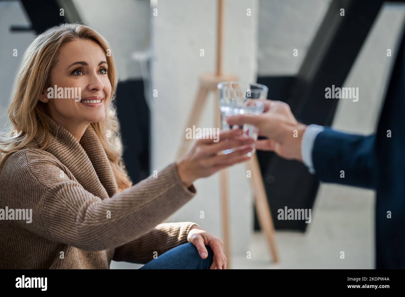 Man in a suit offering a glass of water to the client Stock Photo - Alamy