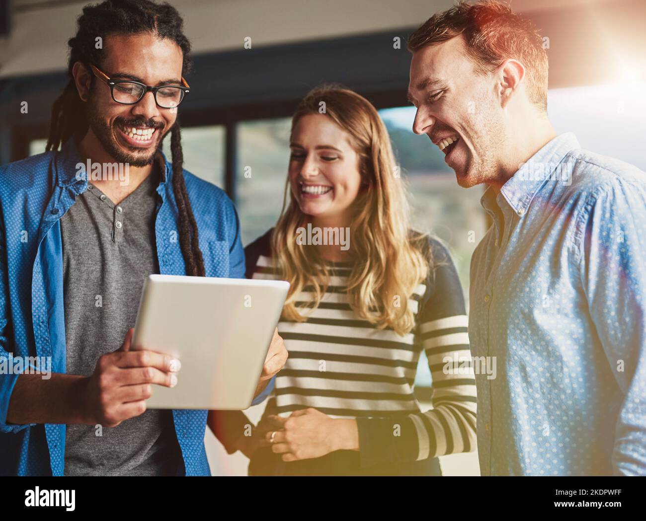 Trading ideas. three young designers talking over a digital tablet in ...