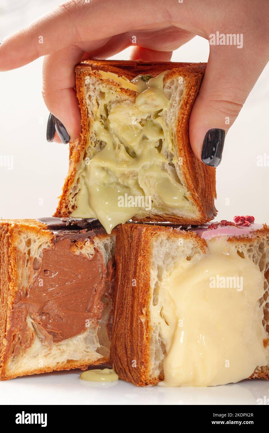 Female hand taking sliced fresh soft cube shaped croissant with ...