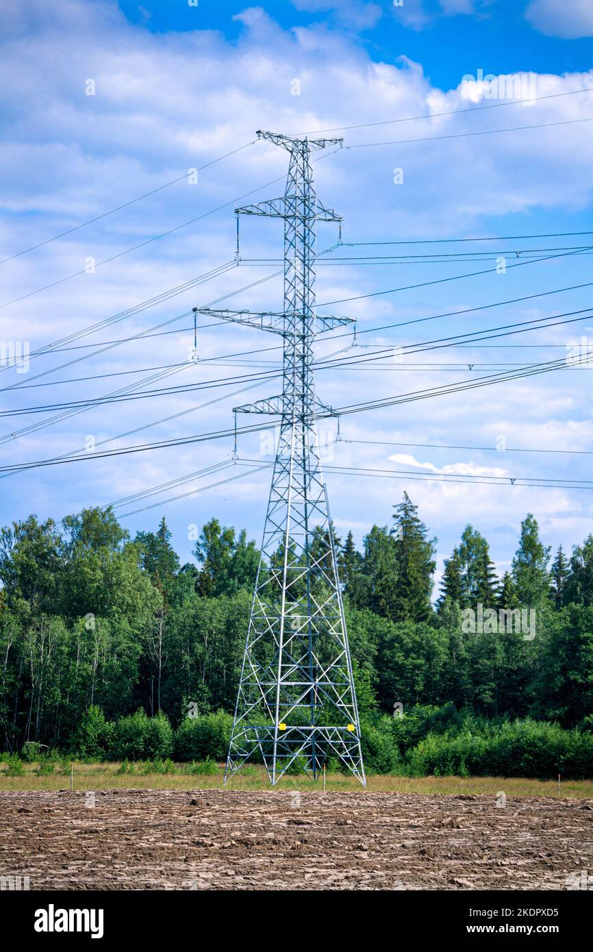 High-rise power transmission tower in a field with wires Stock Photo ...