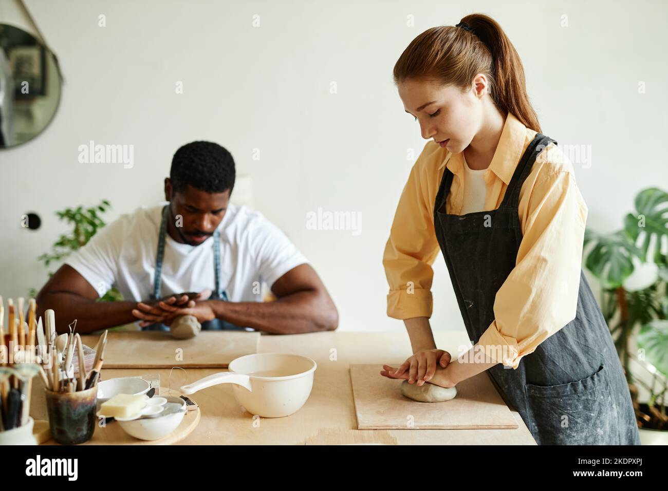 Side view portrait of young woman shaping clay and demonstrating ...