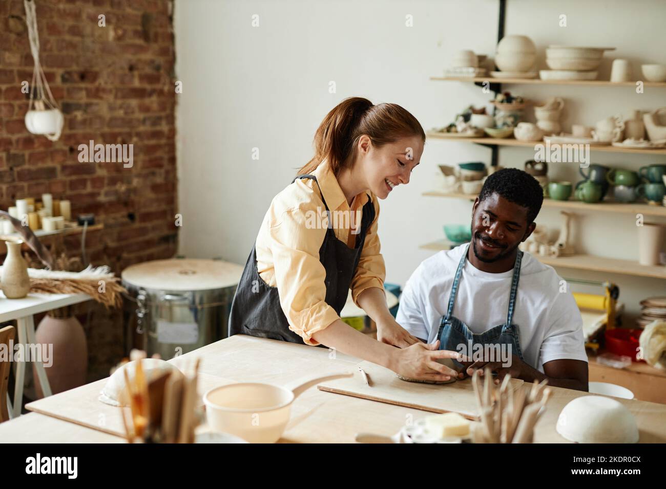 Warm toned portrait of smiling multirational couple making handmade ...