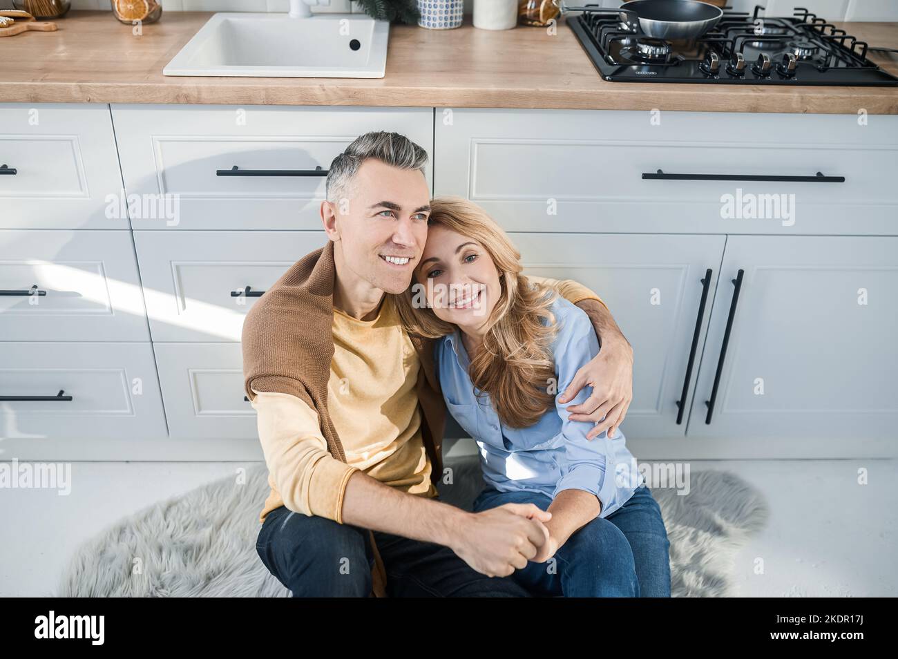 A happy couple sitting in the kitchen and looking joyful Stock Photo ...