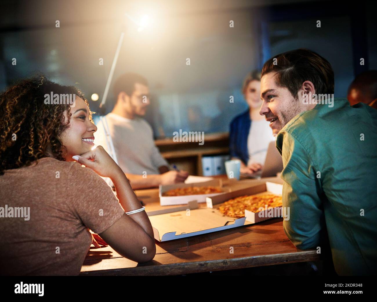 Working late has its perks. a team of young businesspeople eating pizza ...