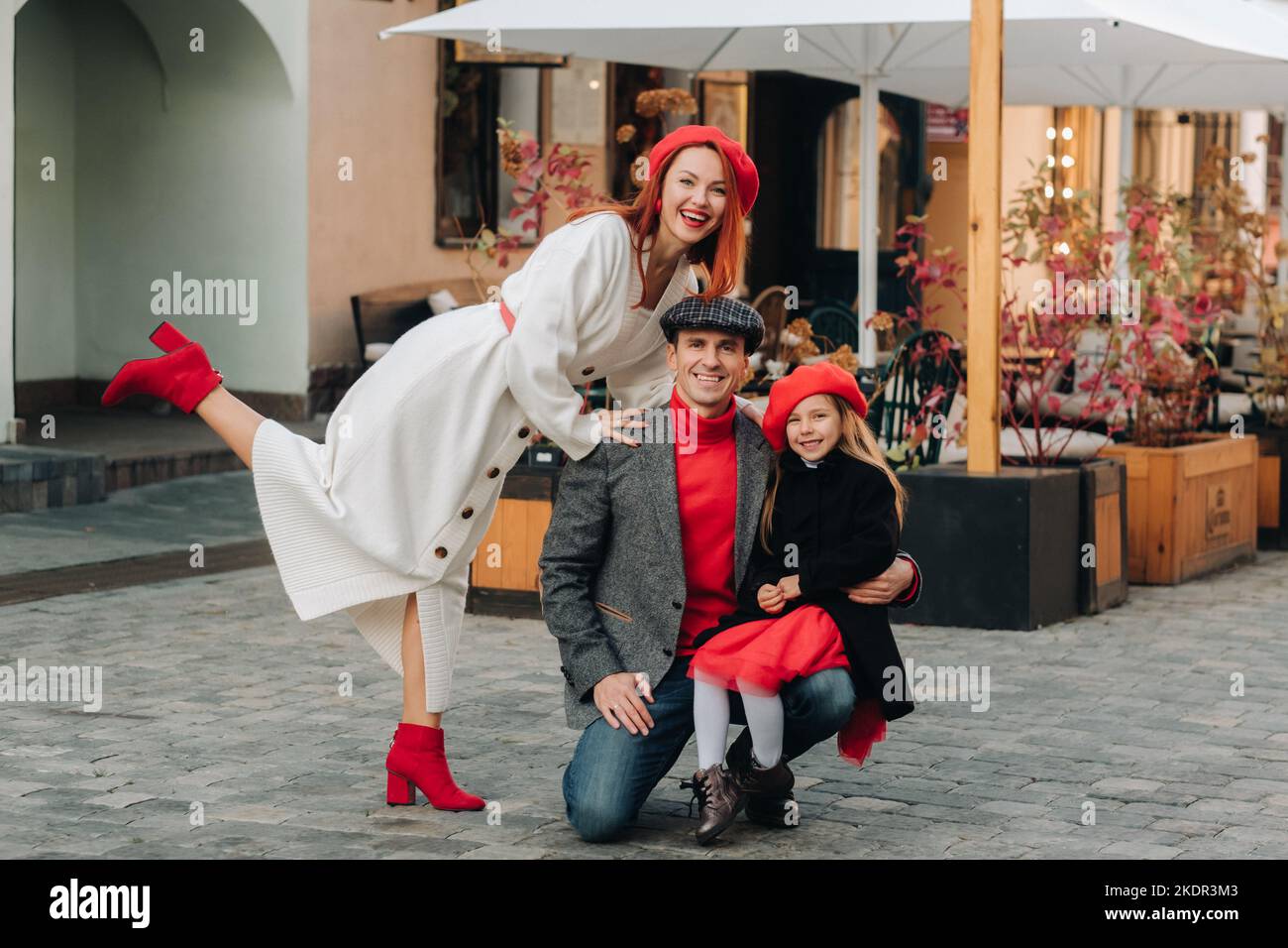A stylish family of three strolls through the autumn city posing for a ...