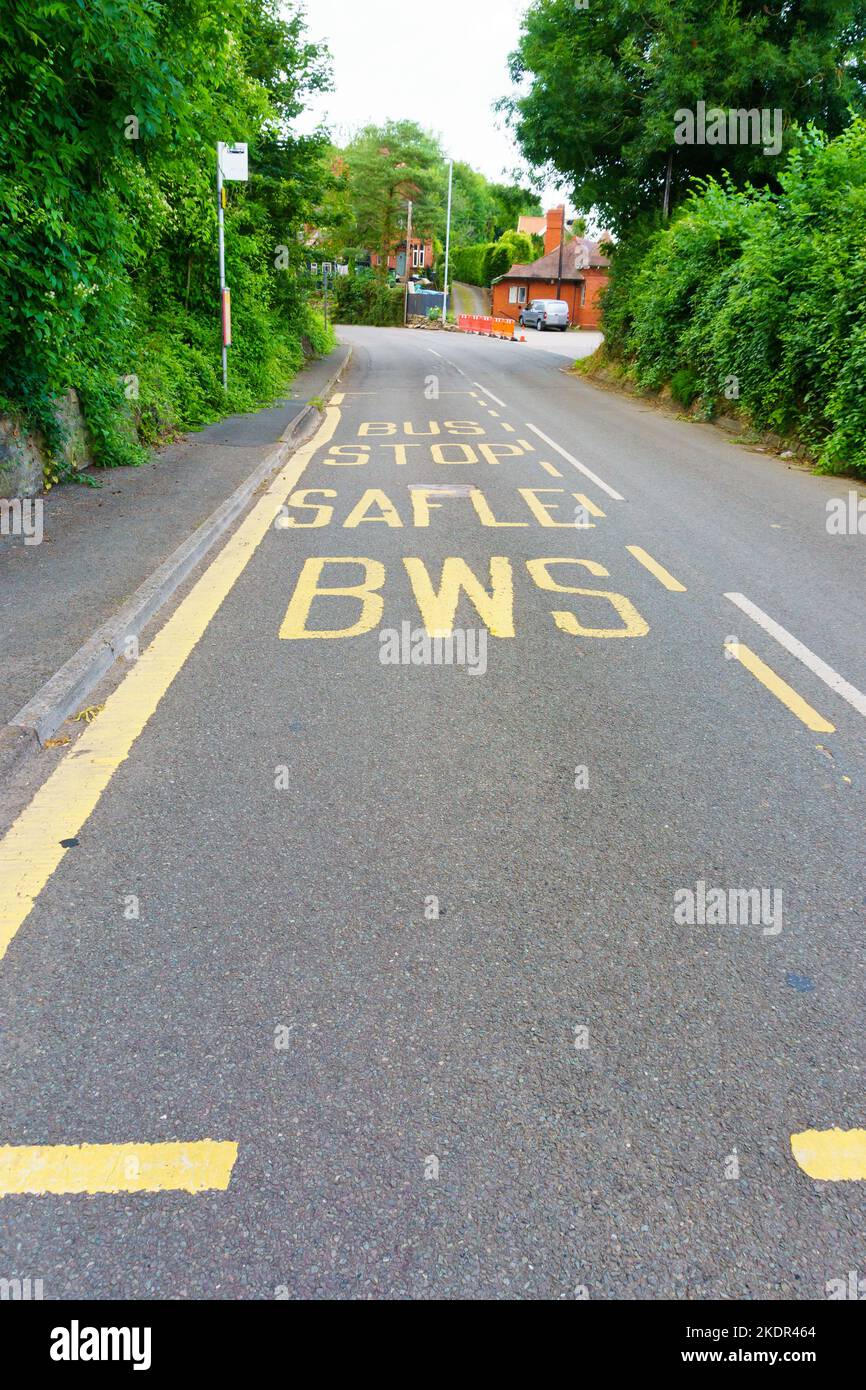 Bilingual road markings sign in English and Welsh at rural bus stop in ...