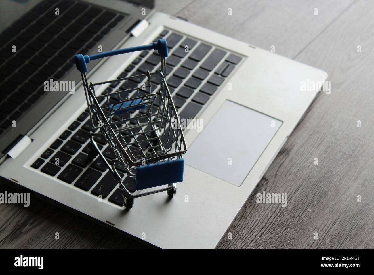Laptop and mini shopping trolley on wooden table. Online shopping ...