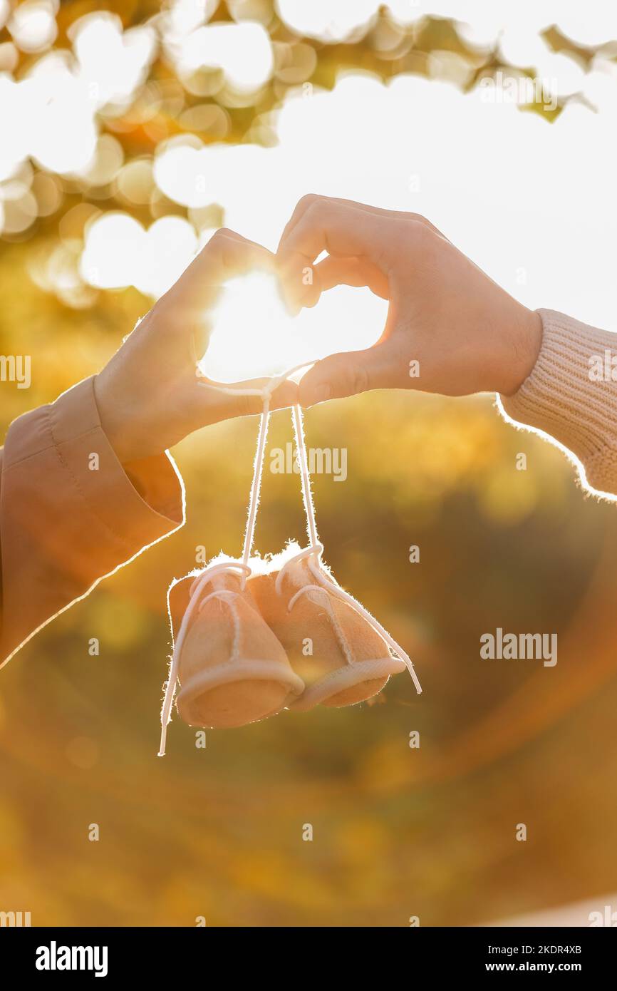 Man and pregnant wife are doing heart gesture with hands and holding ...