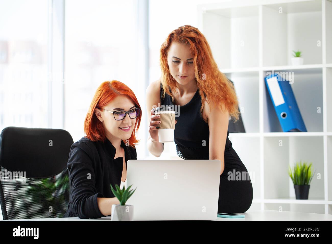 Two red-haired businesswomen in a co-working space with a laptop on the ...