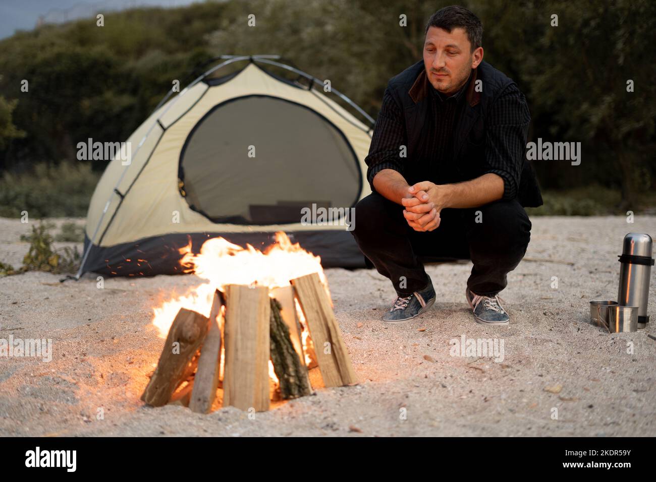Male tourist have a rest in his camp on seashore at the evening. Man ...