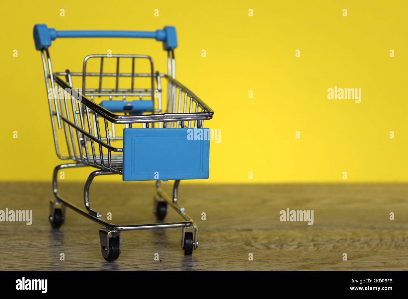 Mini shopping trolley on yellow background with copy space. Shopping ...