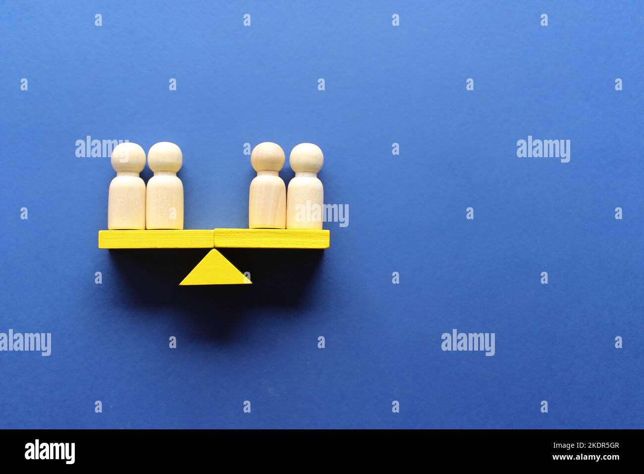 Wooden dolls on balancing scale. Blue background. Team balance and ...