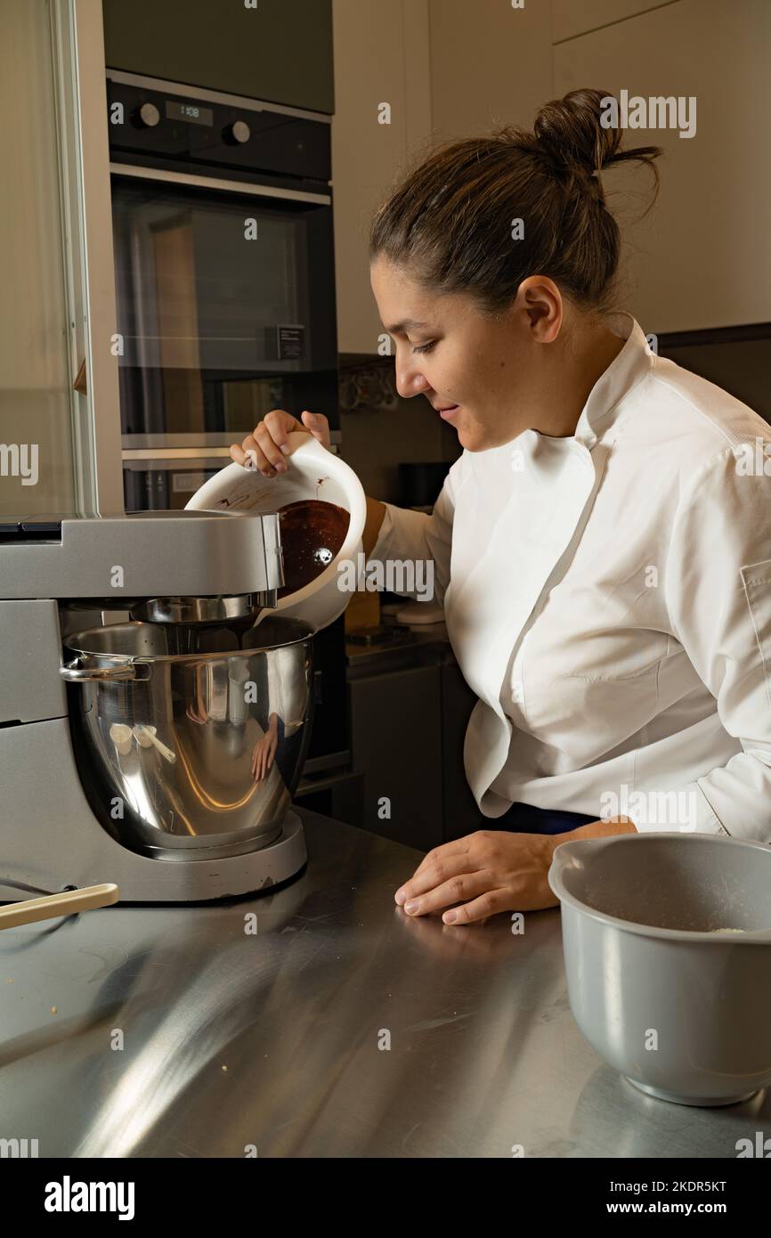 medium-adult woman pastry chef adding chocolate in planetary mixer ... medium-adult woman pastry chef adding chocolate in planetary mixer ...