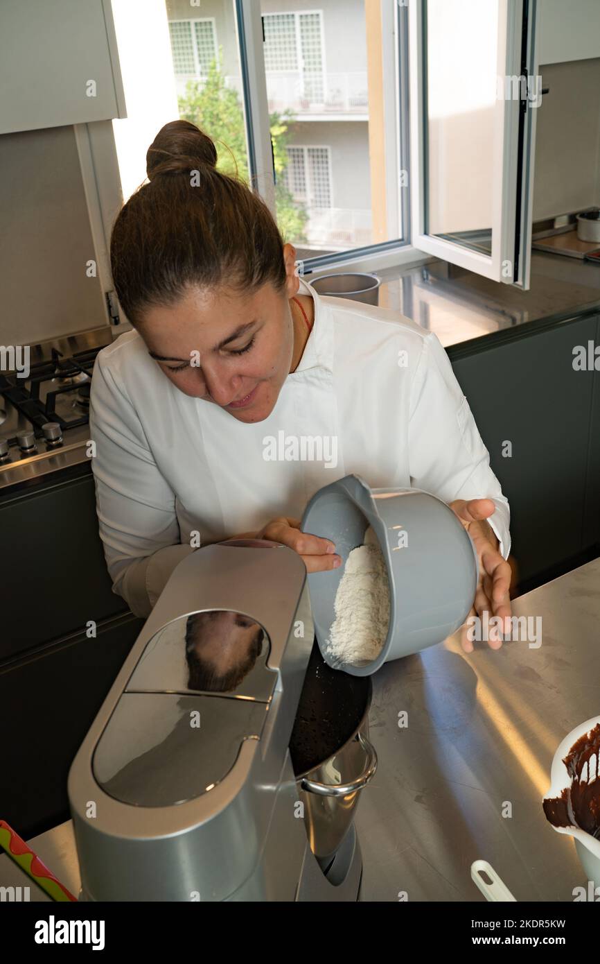 medium-adult woman pastry chef adding flour in planetary mixer, owner ... medium-adult woman pastry chef adding flour in planetary mixer, owner ...