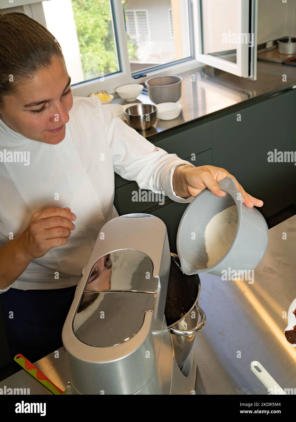 medium-adult woman pastry chef adding flour in planetary mixer, owner ... medium-adult woman pastry chef adding flour in planetary mixer, owner ...