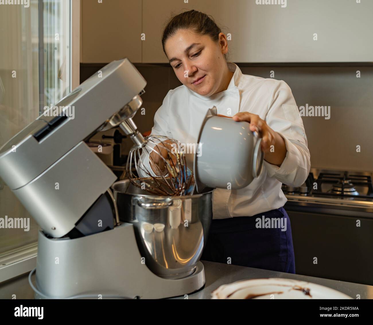 medium-adult woman pastry chef adding flour in planetary mixer, owner ... medium-adult woman pastry chef adding flour in planetary mixer, owner ...