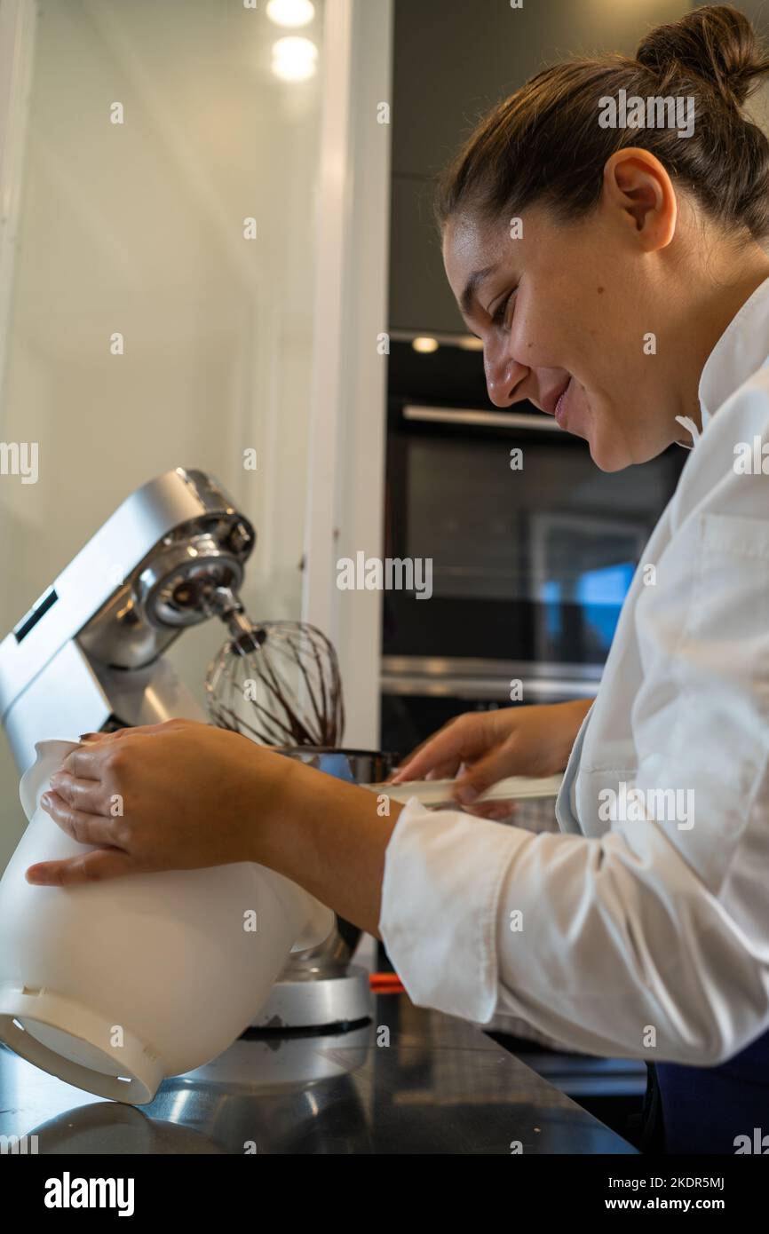 vertical shot of enterprising young woman pastry chef adding chocolate ...