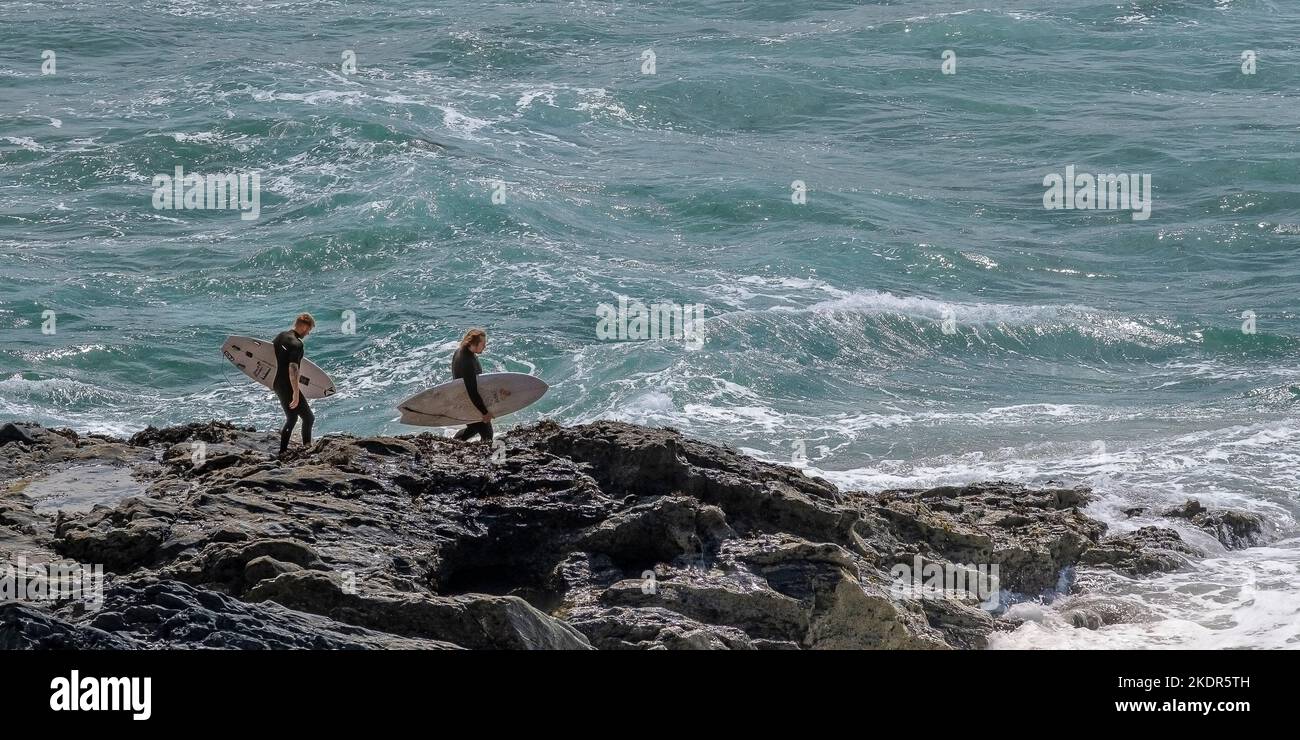 A panoramic image of surfers carrying their surfboards walking along ...