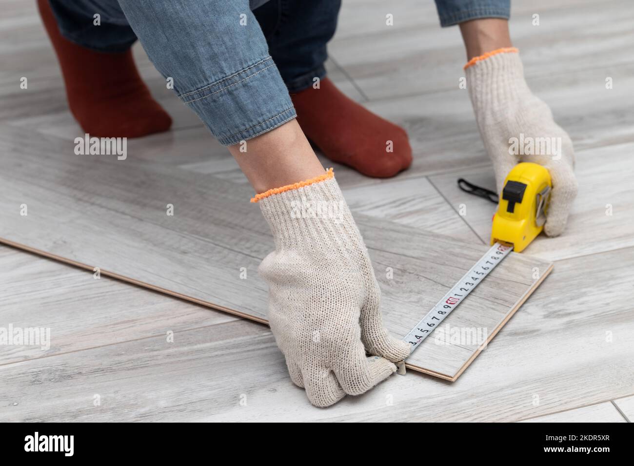 a woman measures the width of a board with a tape measure. handyman ...