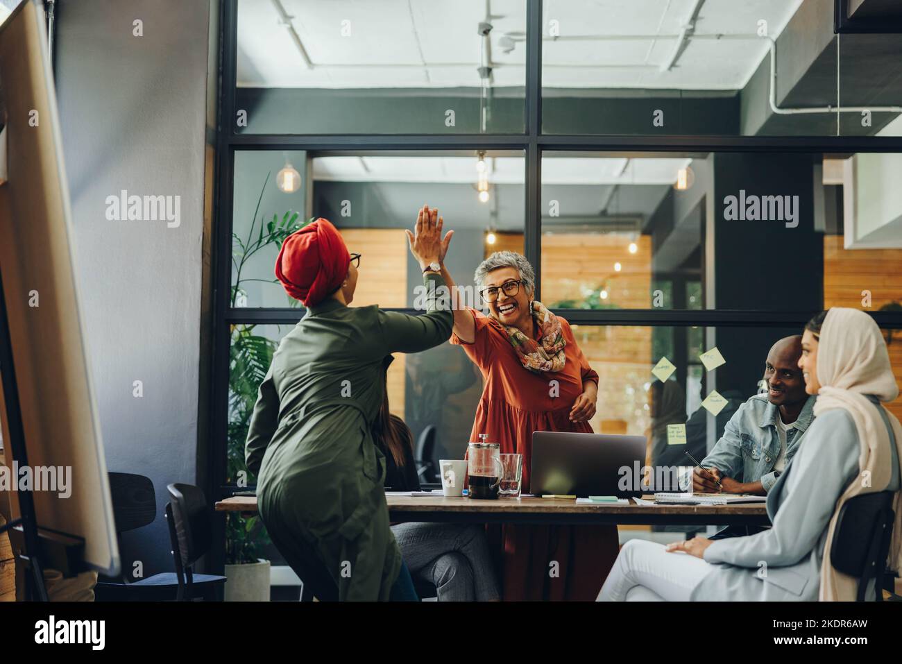 Cheerful businesswomen high fiving each other during an office meeting ...