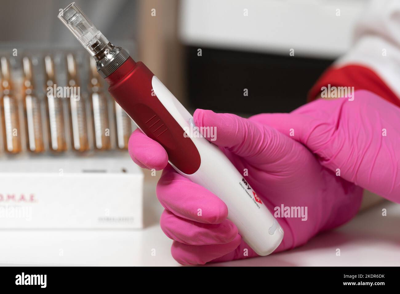 The cosmetologist holds in his hands a dermapen, a tool for mesotherapy ...