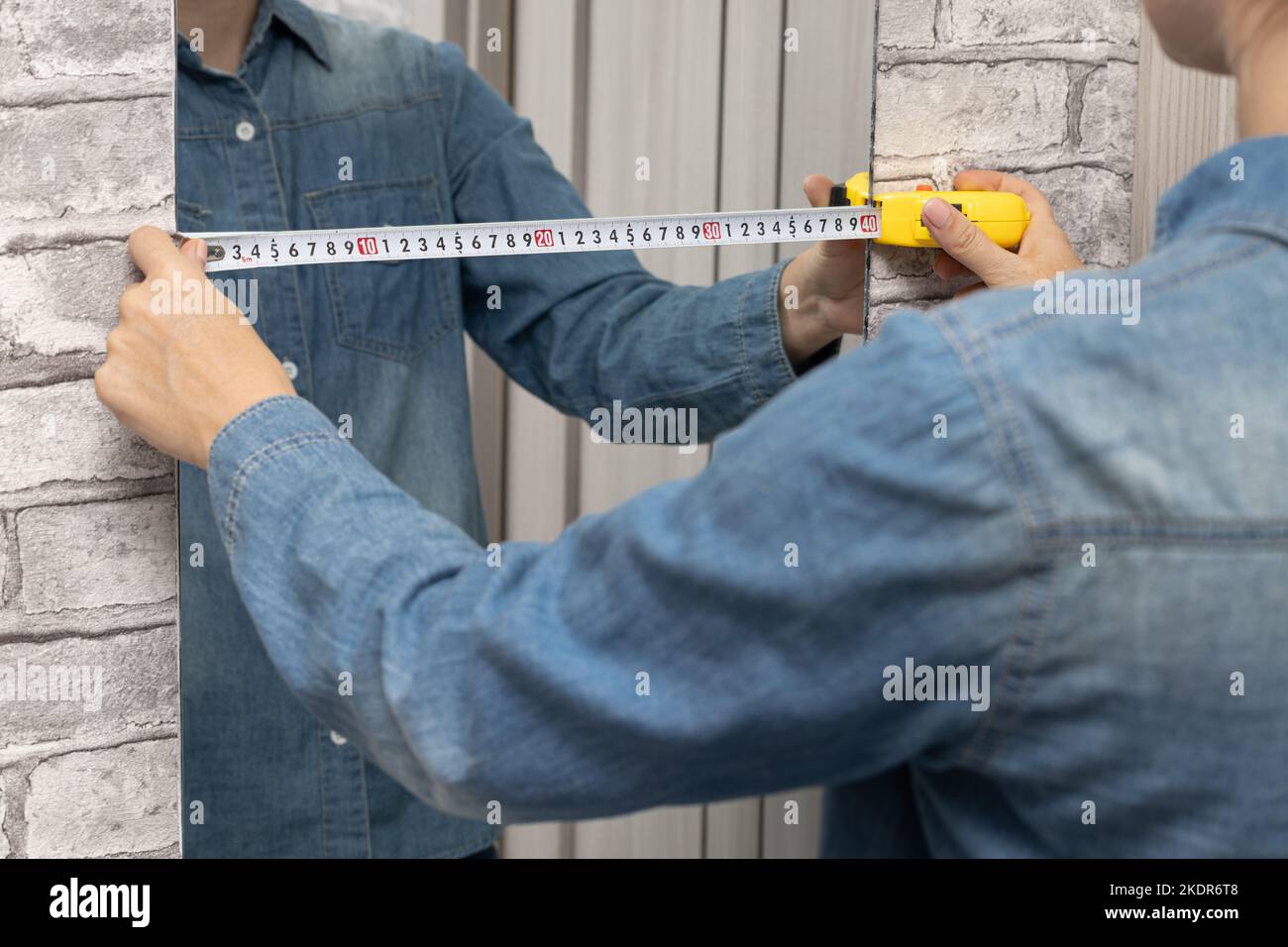 the master measures the width of the mirror. hand holding a tape ...