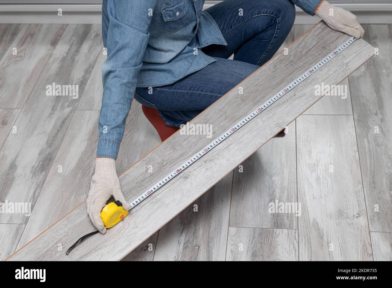 a woman measures the length of a board with a tape measure. High ...