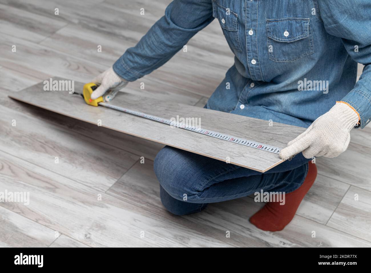 a man measures the length of a board with a tape measure. handyman ...