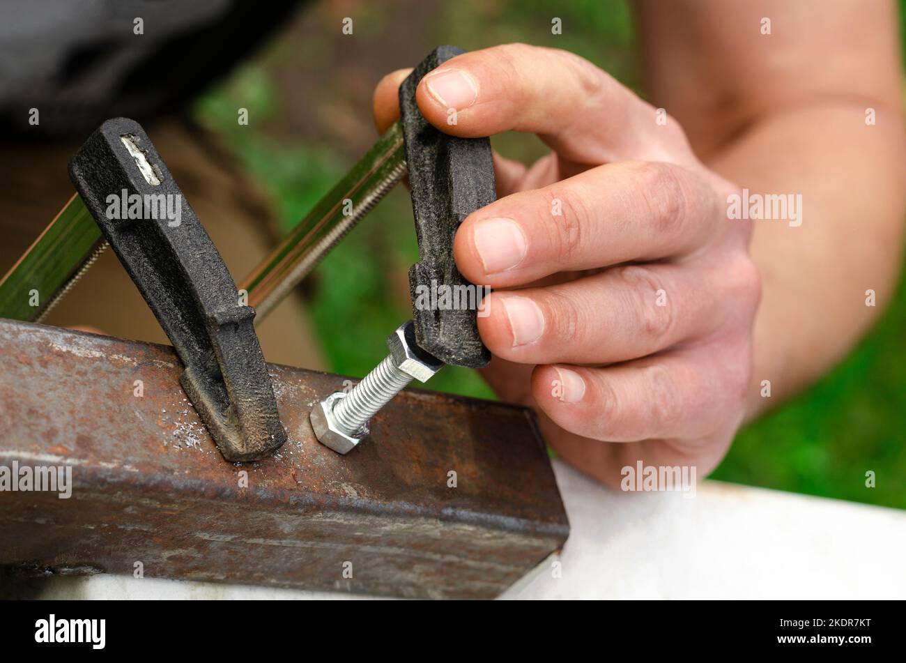 A man's hand screws a bolt into a metal nut. Working with metal Stock ...